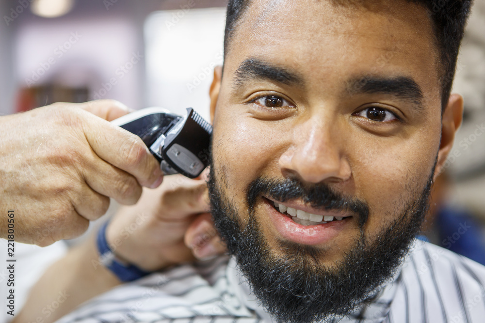 Young black man in a barbershop. Portrait of diverse POC model posing ...