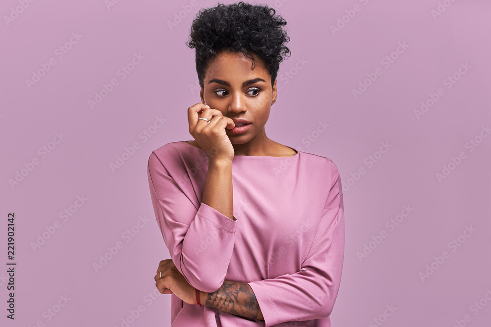 Embarrassed African American woman pursed lips, looks with puzzlement ...