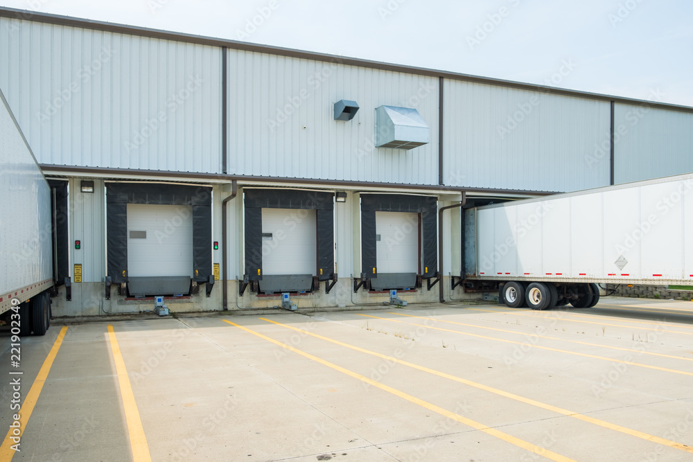 Warehouse building with 53 foot dry van trailers backed into docking ...
