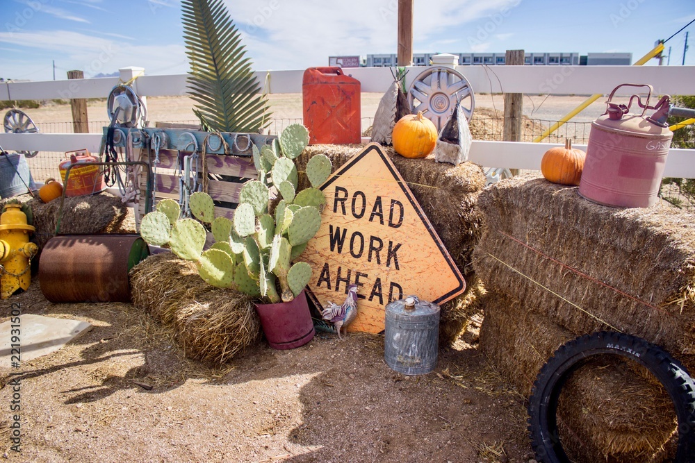 A collection of road signs and desert plants are placed next to bales ...