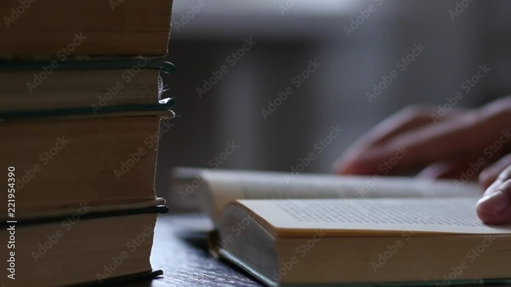 Fingers leafing reading a real paper book at the table in slow motion ...
