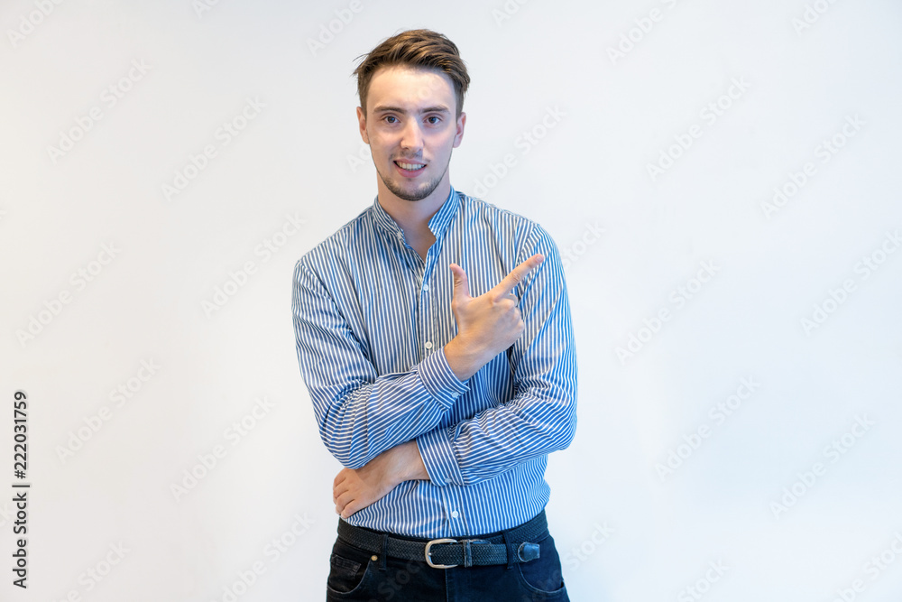 Shocked handsome man pointing with finger aside and looking at camera ...