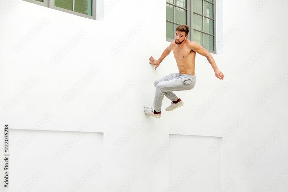 Portrait of a young man jumping on the a wall Stock Photo | Adobe Stock