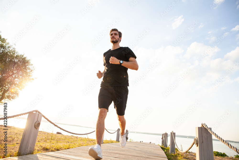 Full length shot of healthy young man running on the promenade. Male ...