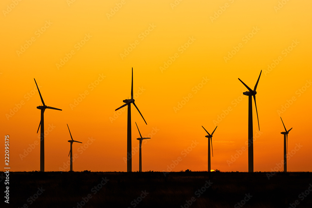 Foto de Large windmills with blades in the field on a bright orange ...