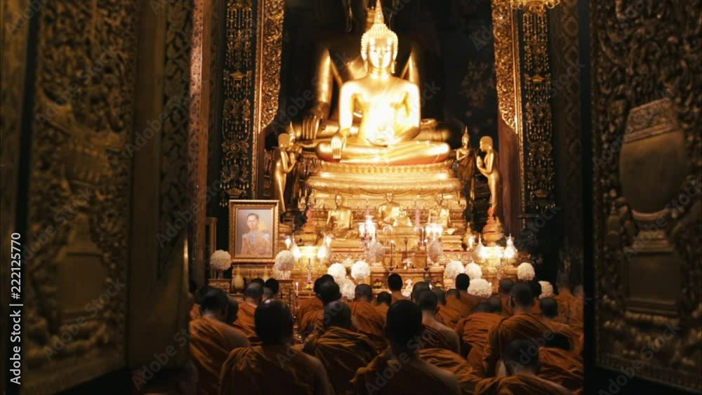 Buddhist monks bending down and praying in front of a giant Buddha a ...