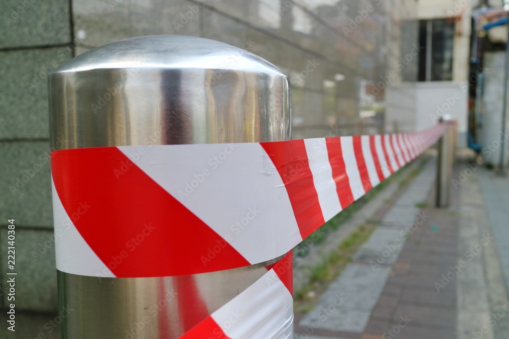 Pole with red and white lines of barrier tape at no entry area. Sign ...