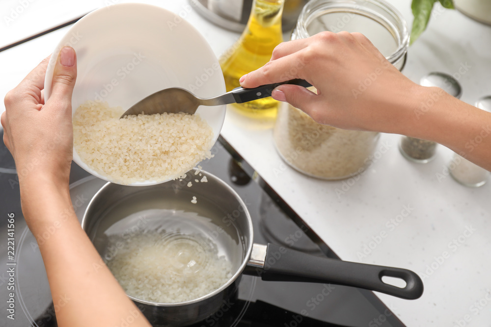 Woman pouring raw rice into saucepan with boiling water on stove Stock ...