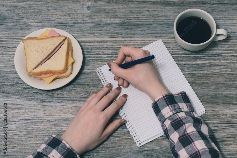 Top view on woman's hand writing in notepad. Background of plate with ...