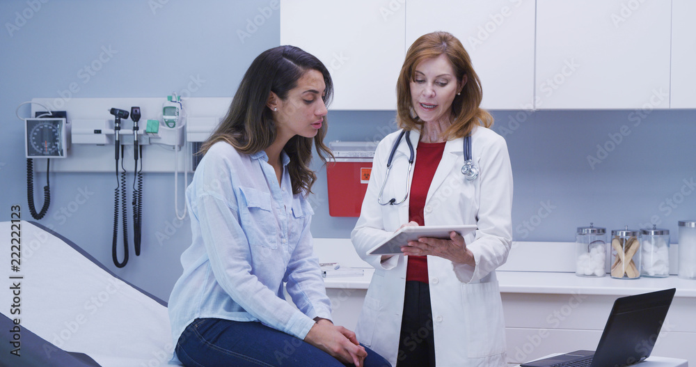 Lovely young latina patient sitting in medical clinic consulting with ...