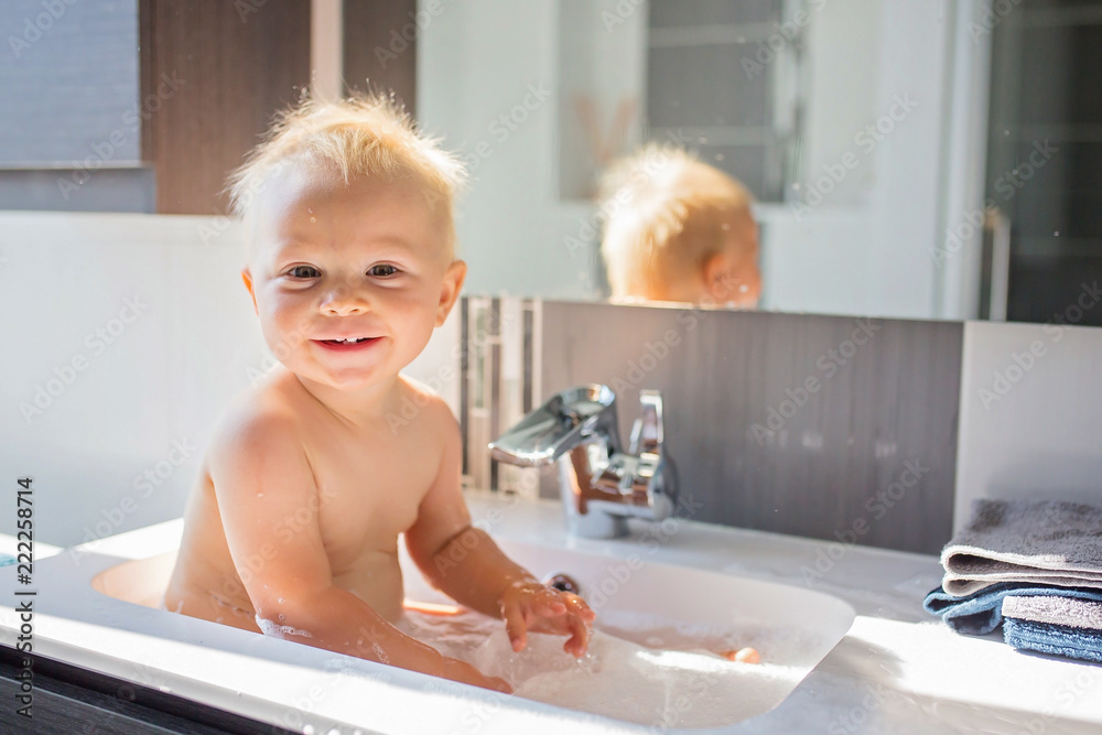 Baby taking bath in sink. Child playing with foam and soap bubbles in ...