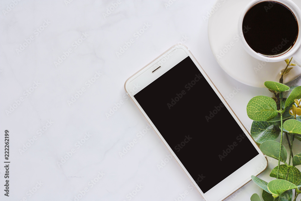 Smartphone with cup of coffee and leaf bouquet on white marble ...
