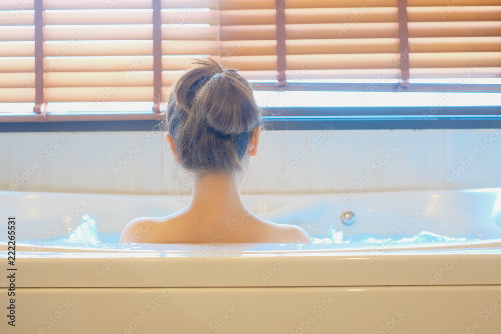 Beautiful spa. Back view of a young woman enjoying bathtub in a spa ...