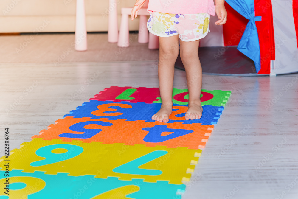 Cute little girl walks and jumps over play mat Stock Photo | Adobe Stock