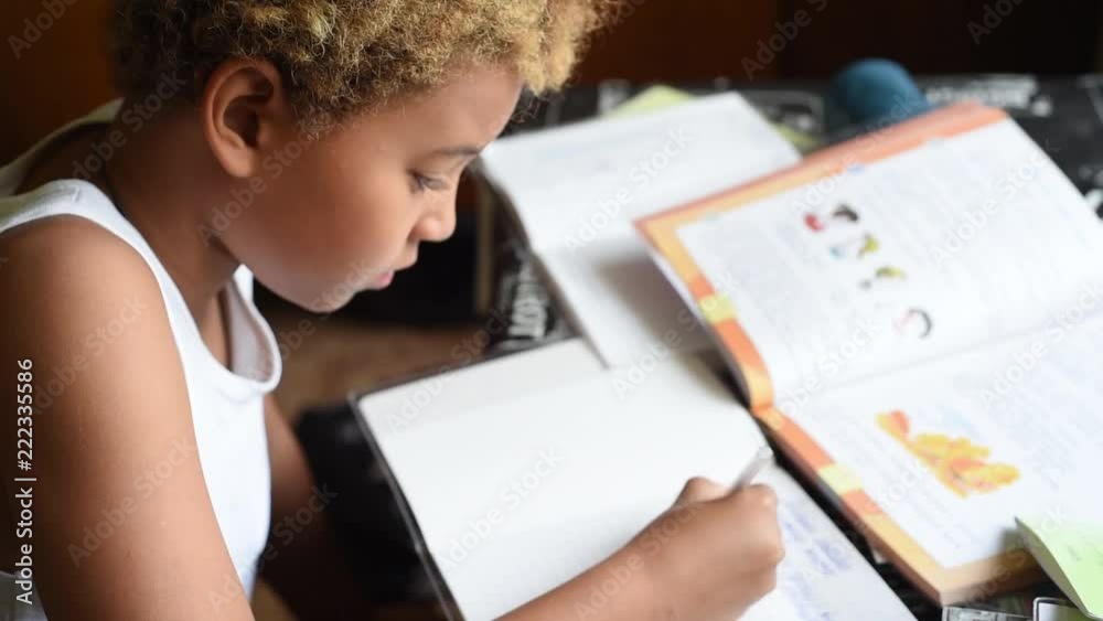 Schoolboy doing homework in his room in the home. Cute african american ...