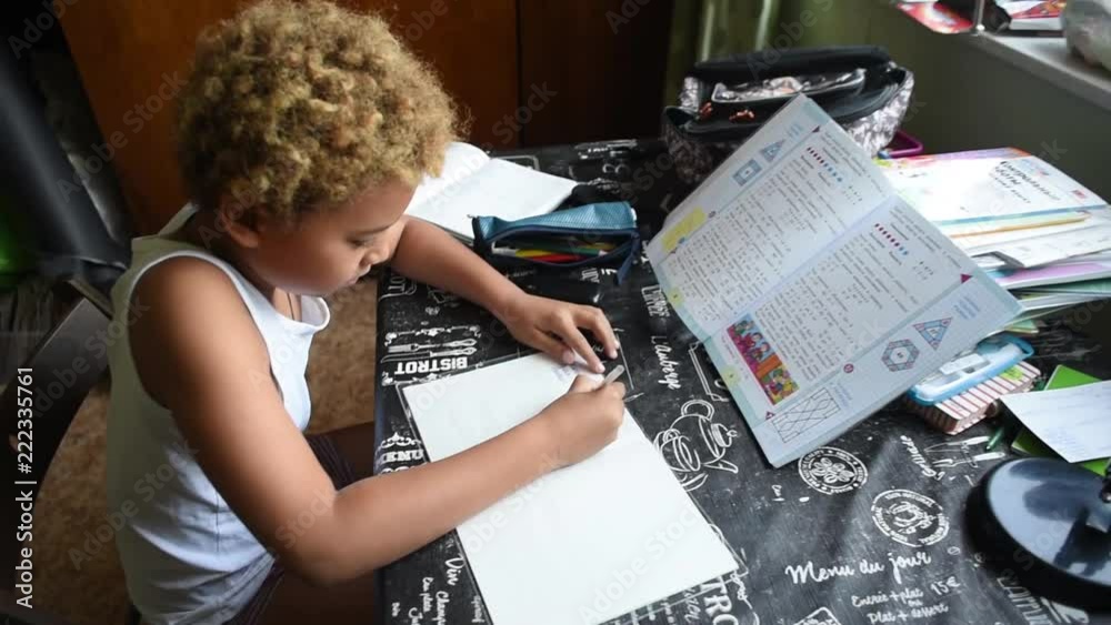 Schoolboy doing homework in his room in the home. Cute african american ...