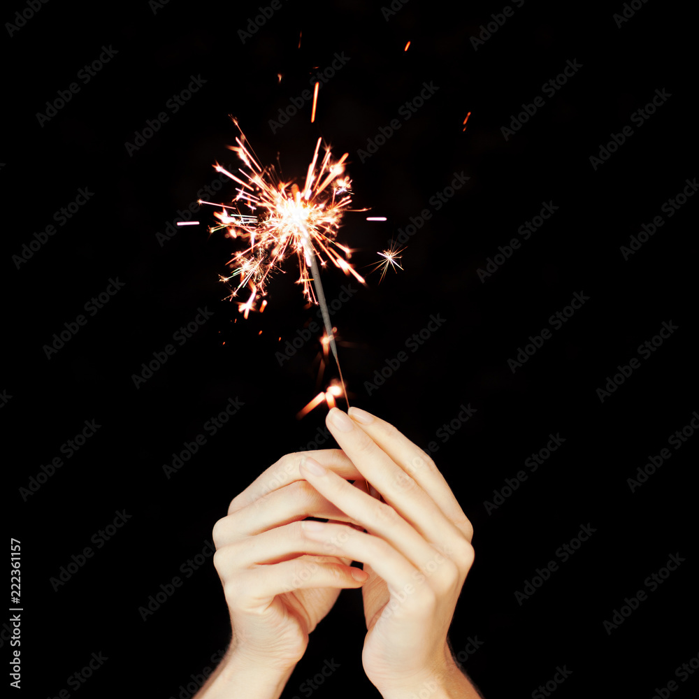 Beautiful woman hands holding sparkler lights in front of black, can be ...