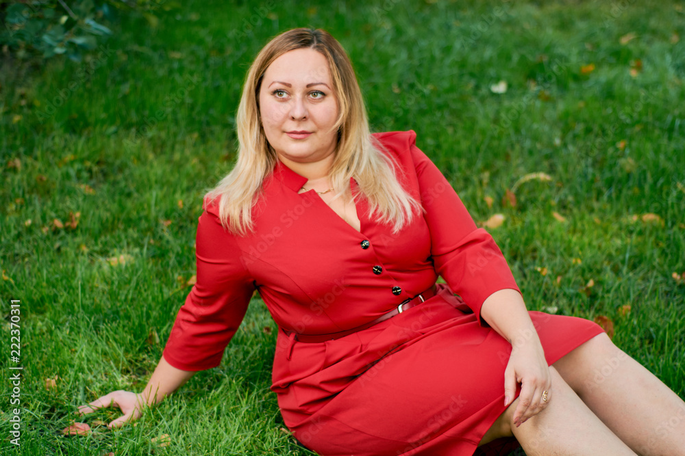 Portrait of a beautiful girl with overweight in a red dress. Close-up ...