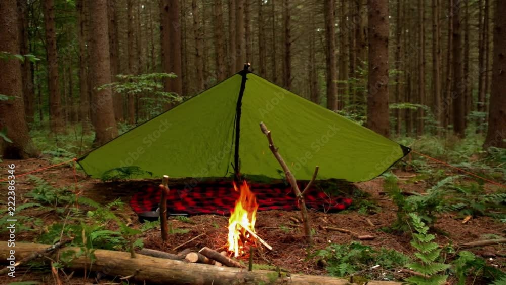 Raging campfire in front of bushcraft style tarp setup. Footage of a ...