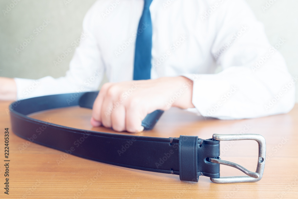 Office Man in white shirt and tie is holding a belt, punishment concept ...