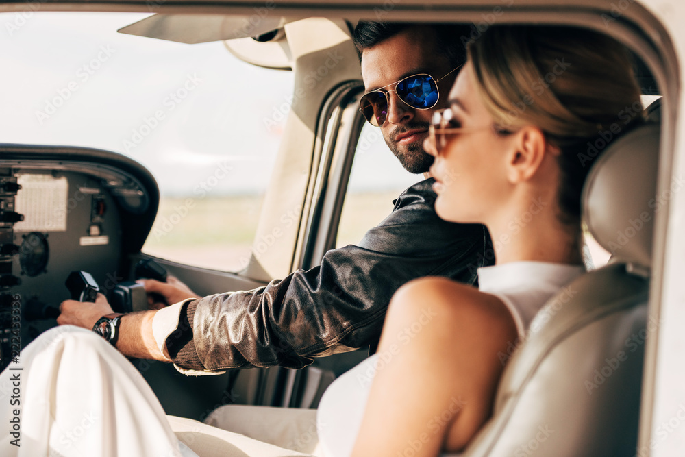 stylish male pilot in sunglasses and leather jacket looking at camera ...