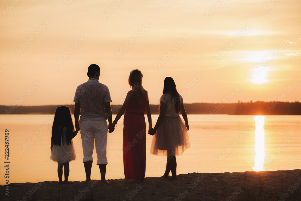 Silhouizes a friendly traditional family (mom, dad, daughter) at sunset ...