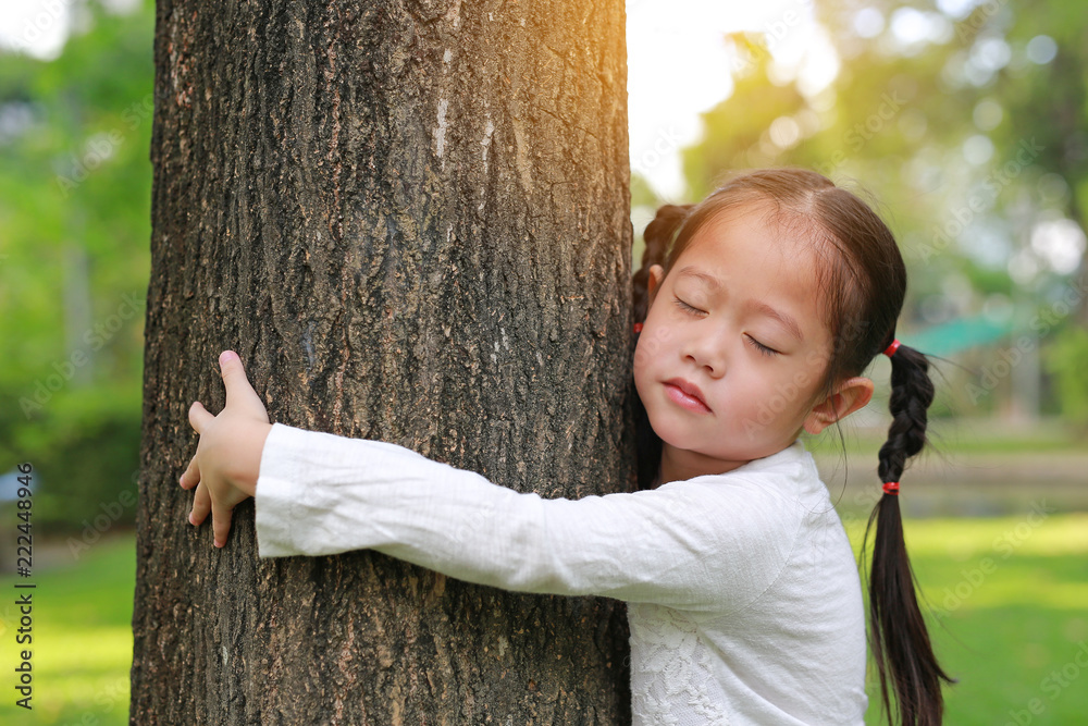 Portrait of cute little child girl and nature. Kid hugging a tree ...