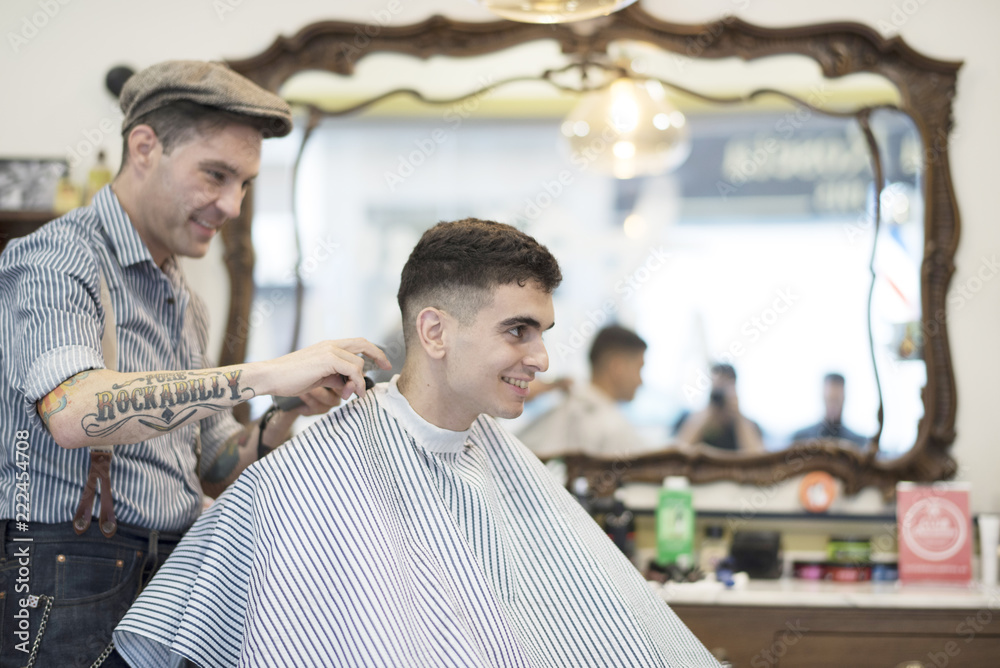 Barbero moderno con vestimenta vintage corta el pelo a joven muchacho ...