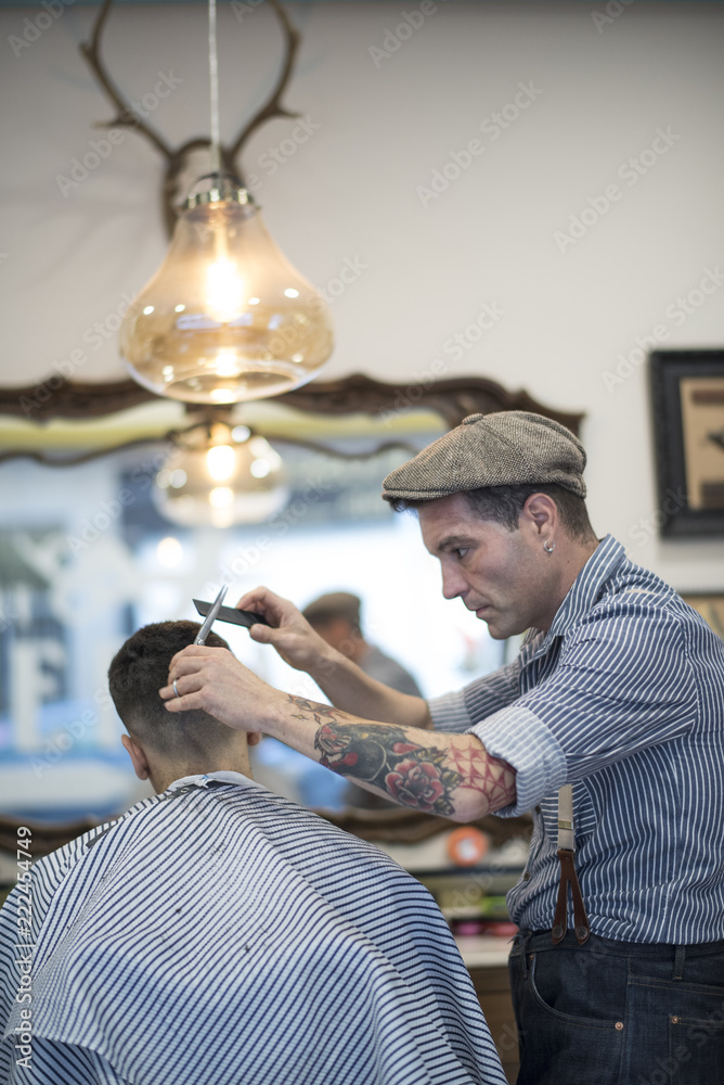 Barbero moderno con vestimenta vintage corta el pelo a joven muchacho ...