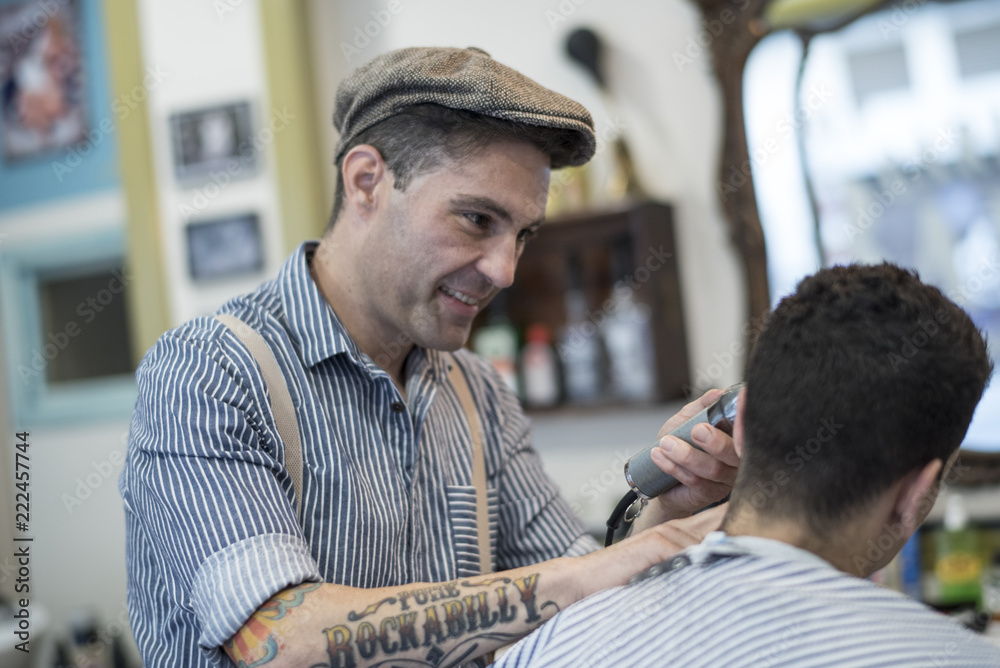 Barbero moderno con vestimenta vintage corta el pelo a joven muchacho ...