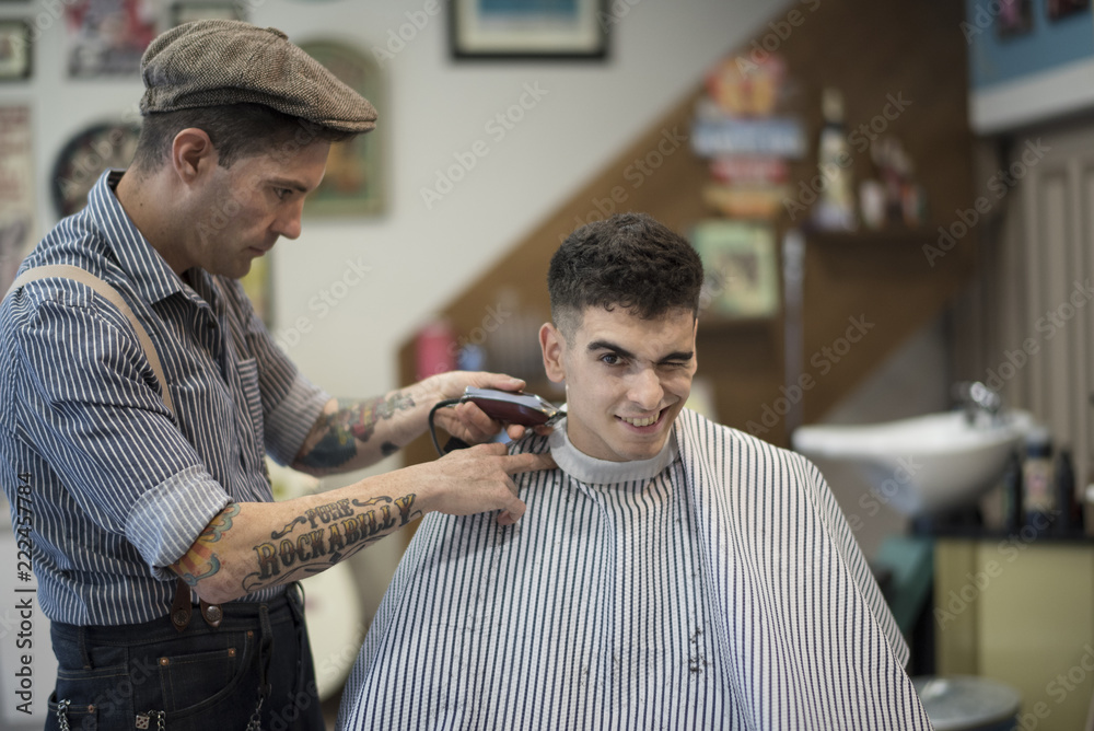 Barbero moderno con vestimenta vintage corta el pelo a joven muchacho ...