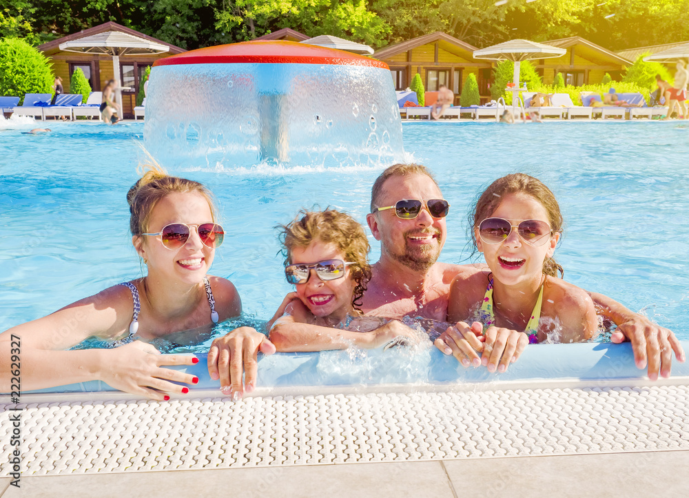 Happy family in the pool, having fun in the water, dad with three kids ...