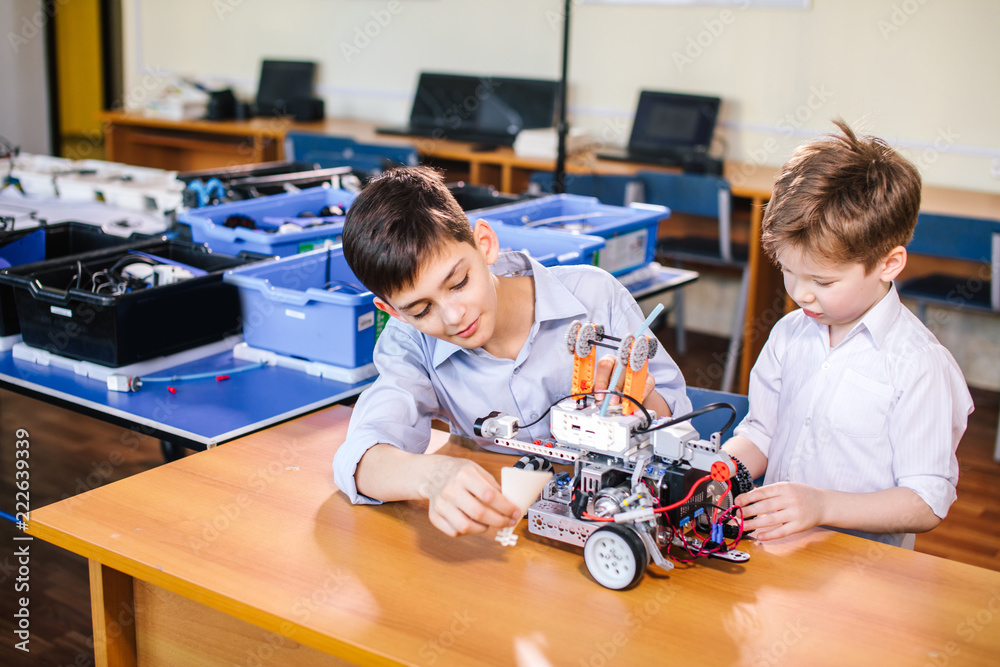 Two brothers kids of different age playing with robot toy at school ...
