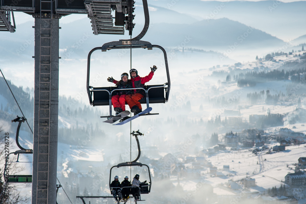 Couple snowboarders having fun on a ski lift in ski resort with ...