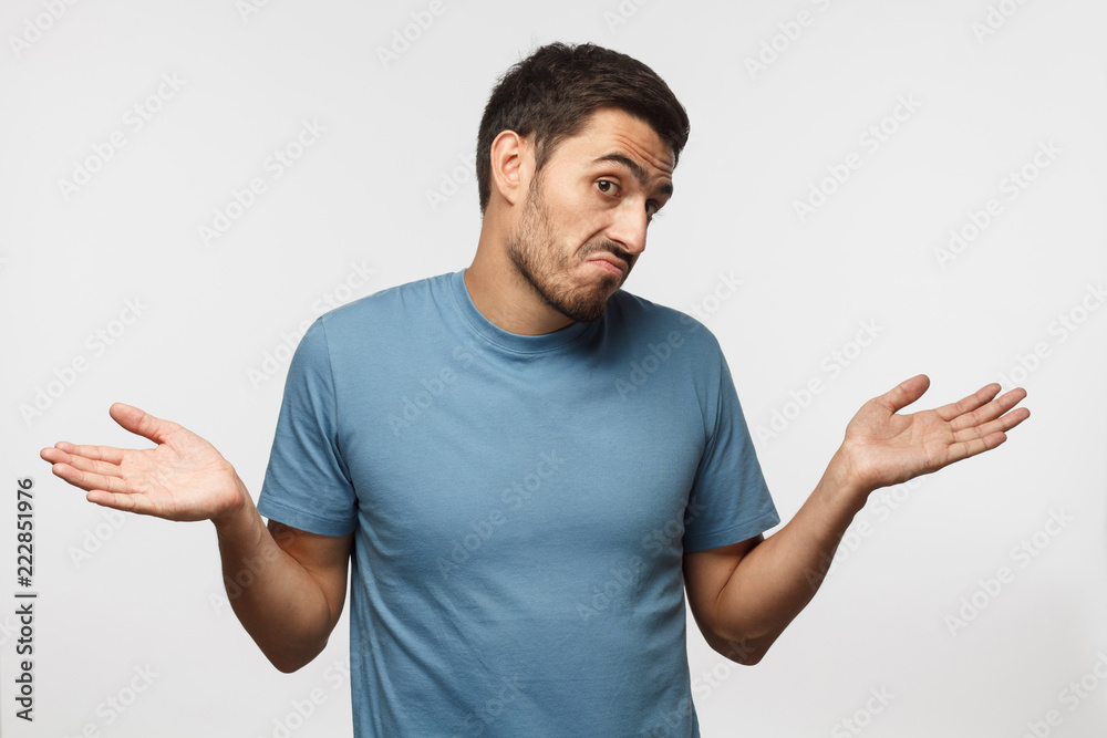 I don't know. Young man isolated on gray background, showing helpless ... I don't know. Young man isolated on gray background, showing helpless ...
