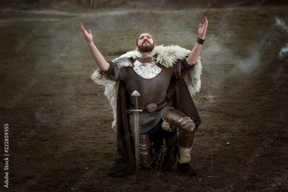 Knight in armor knelt down and pray raised his head to heaven. Stock ...