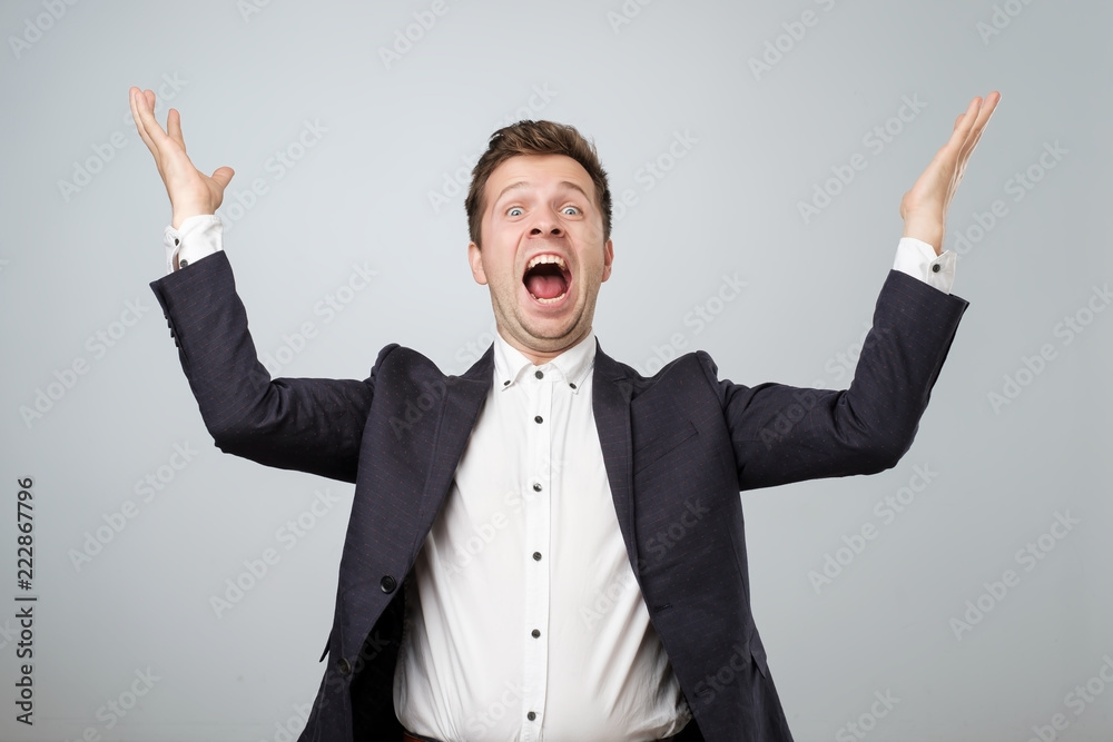 Portrait of excited young male in suit screaming in shock and amazement ...