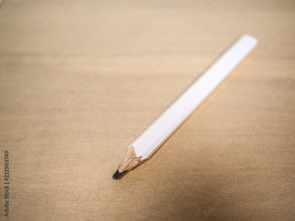 Macro photograph of a single white carpenters pencil on a light wood ...