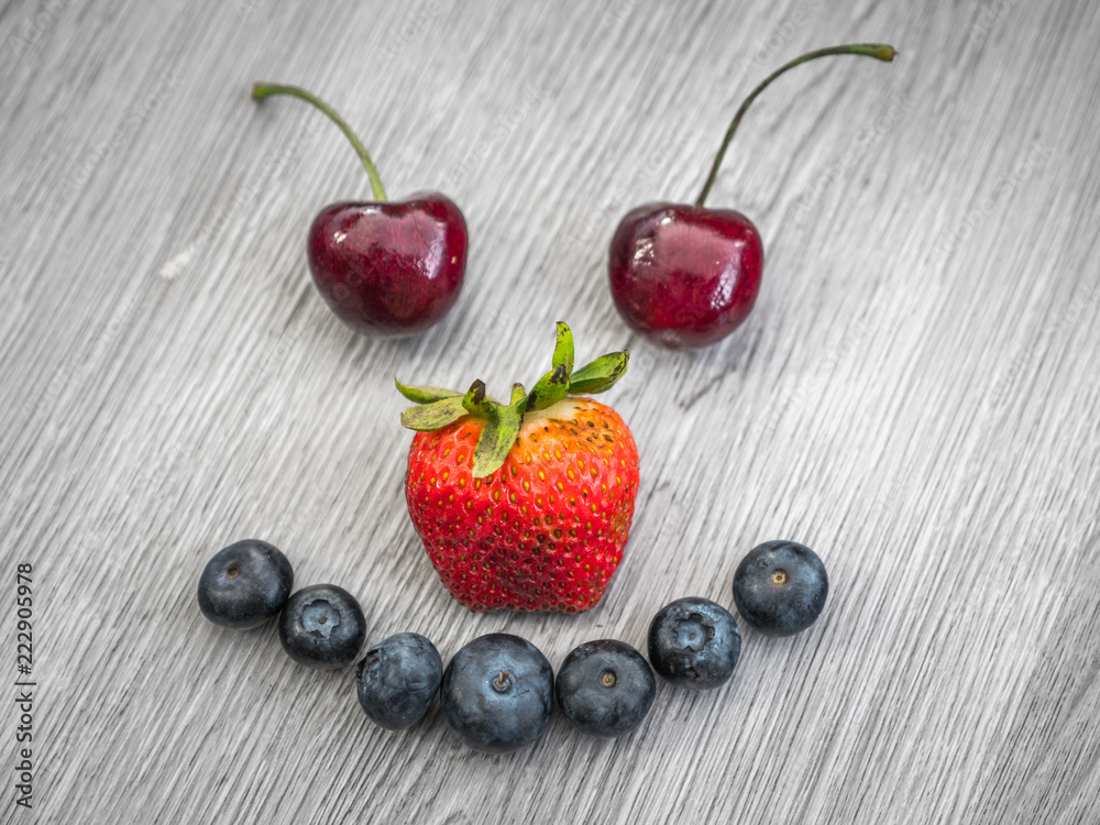 Silly smiley face composed with ripe fruit including cherry eyes ...