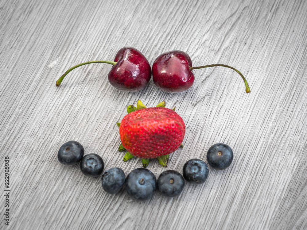 Silly smiley face composed with ripe fruit including cherry eyes ...