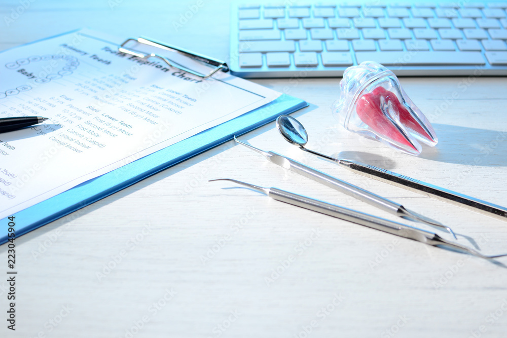Dentist tools, tooth eruption chart and tooth model on dentist table ...