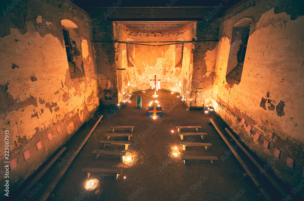 Worship in mysterious church interior with lighting candles and cross ...