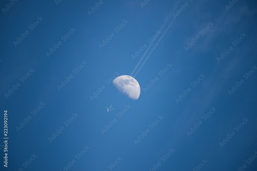 plane passing through the Moon from bottom view with long condensation ...
