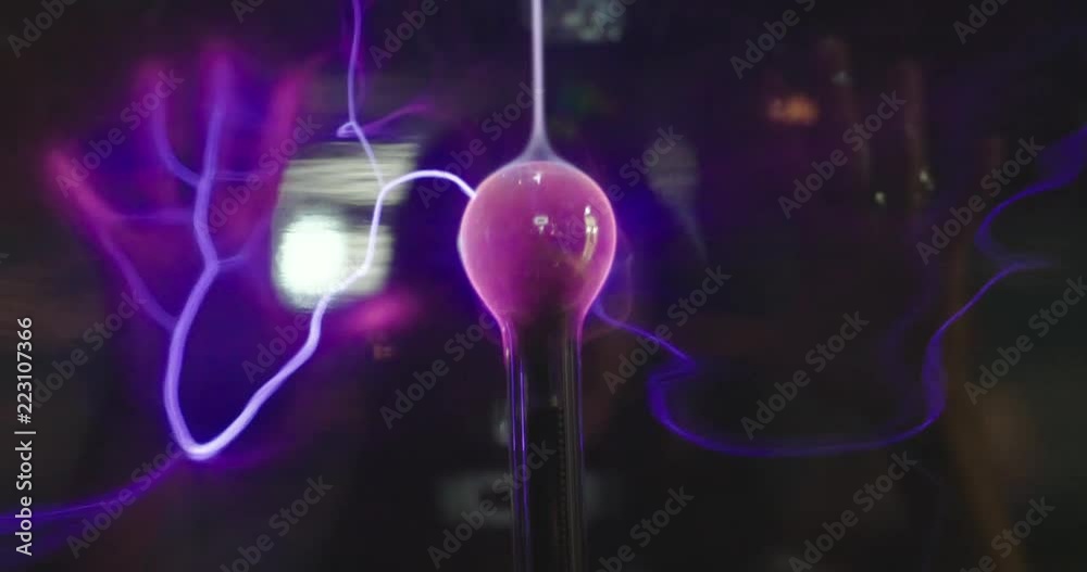 Close up of a hand touching a tesla coil that contains electricity ...