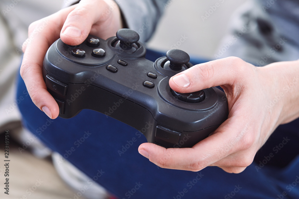 man holding a joystick controllers while playing a video games at home ...