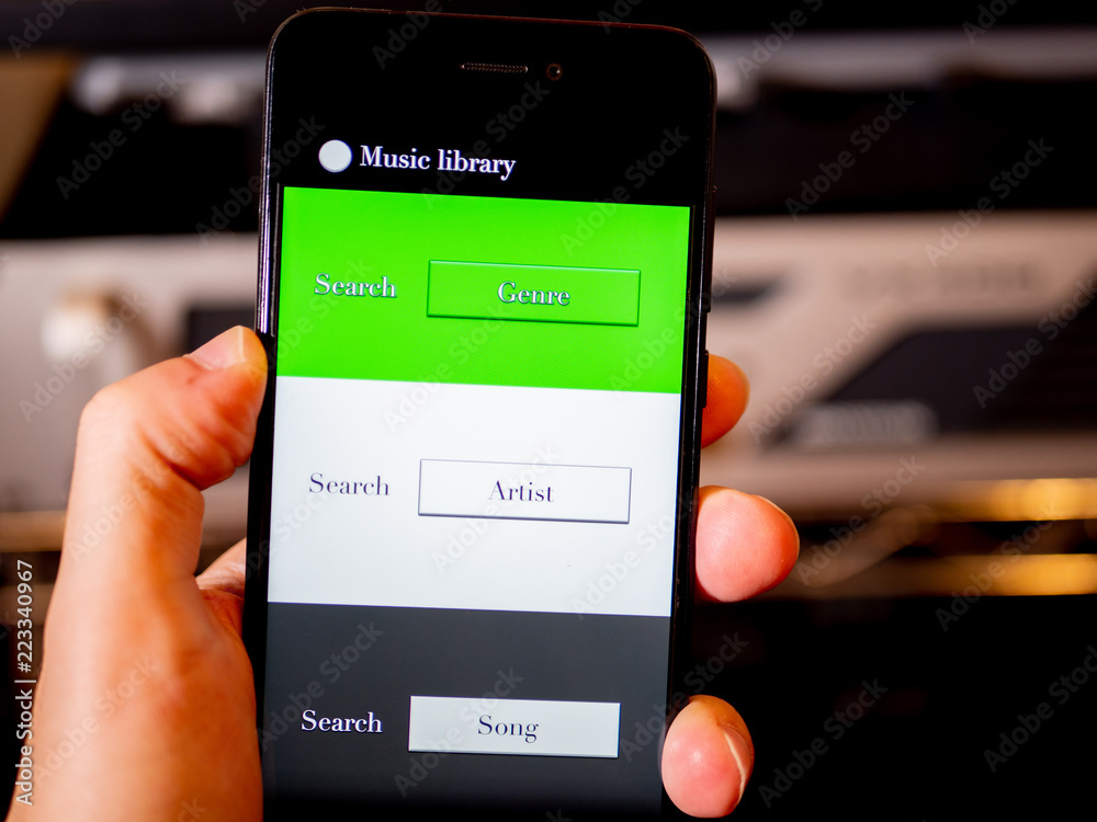 Hand holding a phone with music app in front of sound system. First ...