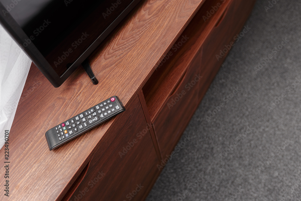 Tv and remote control on the brown wooden table Stock Photo | Adobe Stock