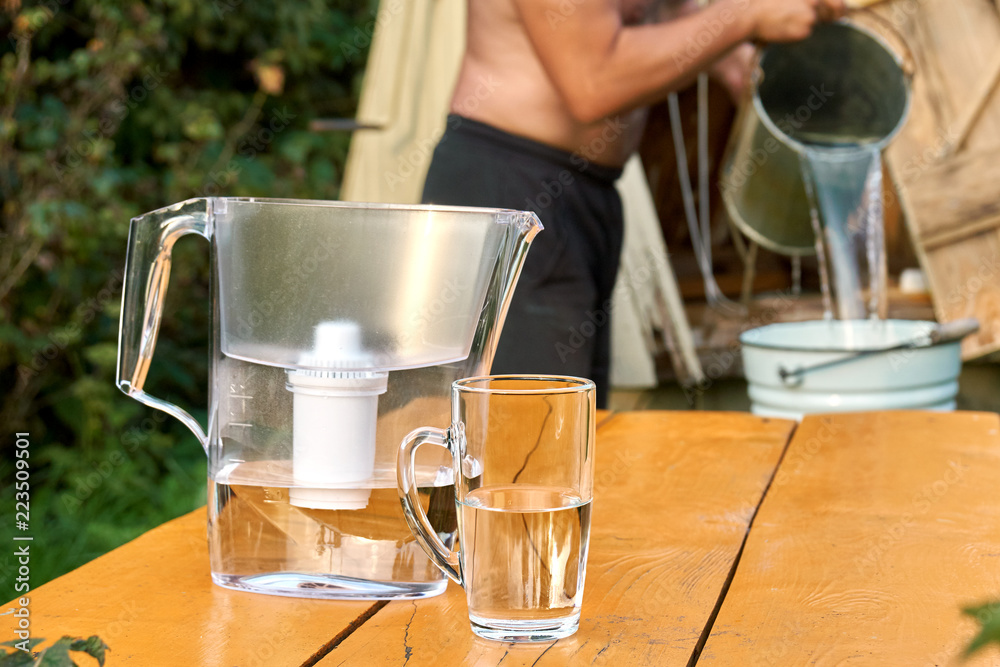 Water filter with a transparent cup of water with a shirtless man ...