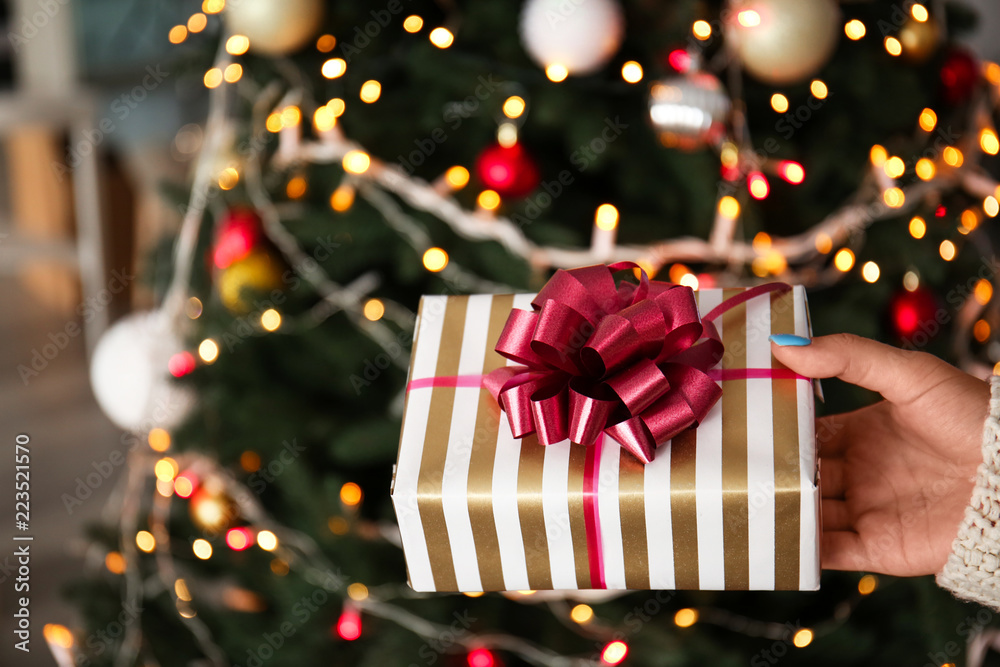 Woman holding beautiful gift near Christmas tree Stock Photo | Adobe Stock