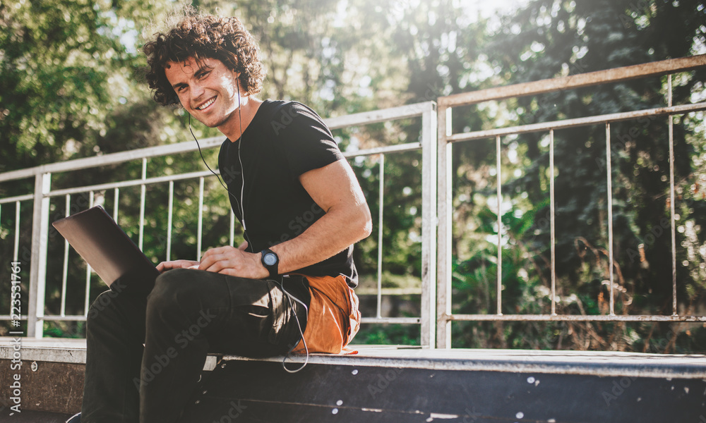 Horizontal image of cheerful Caucasian male using laptop computer and ...